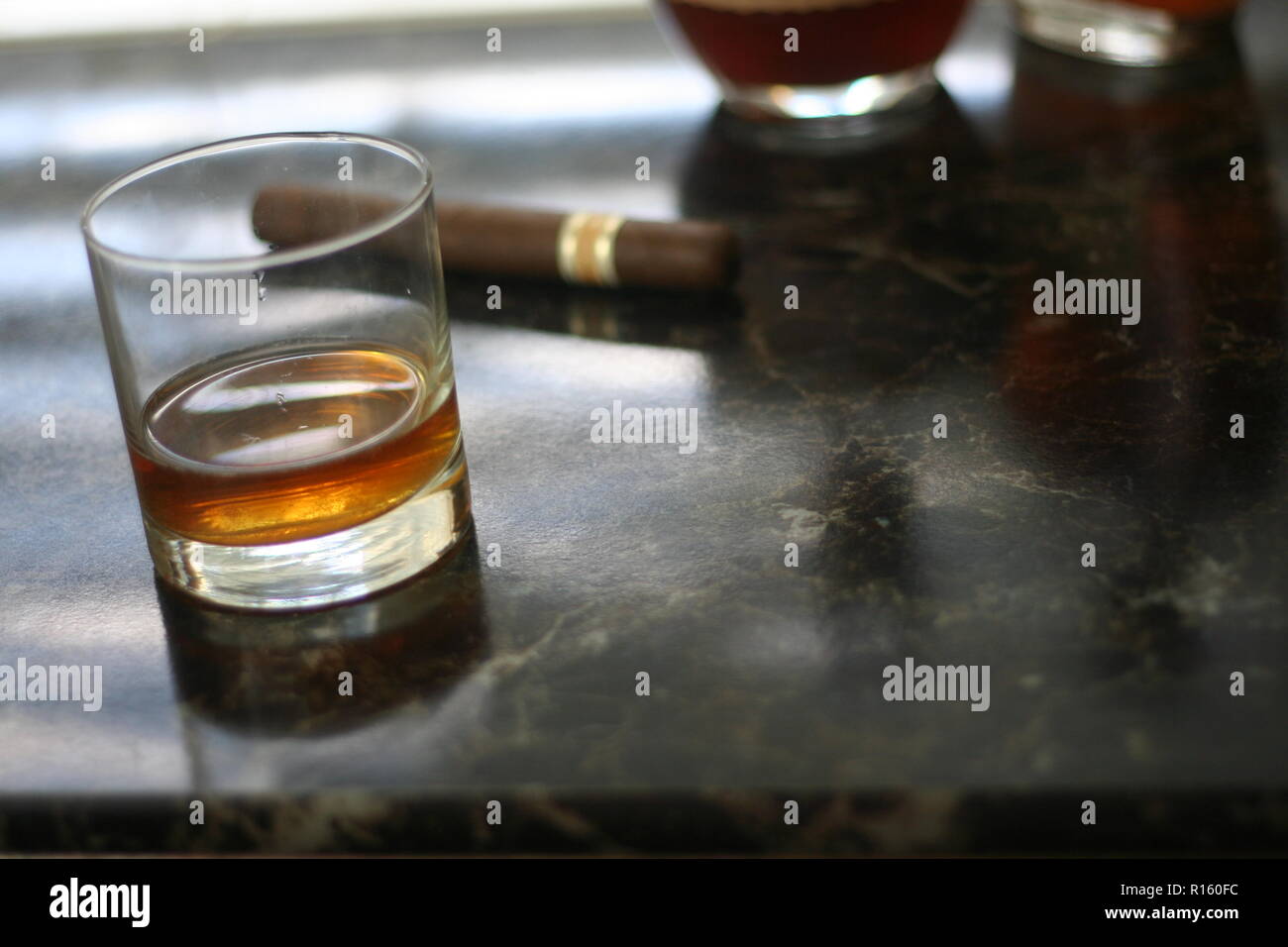 Whiskey glass, bottles and cigar on marble table Stock Photo - Alamy