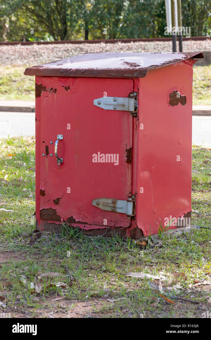 A Close up side view of a red old rusted post offcie post box storage ...