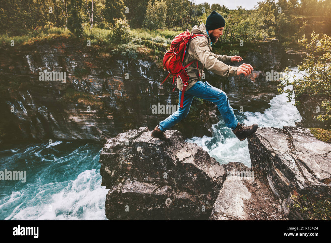 Adventure man jumping on rocks over river canyon traveling active ...