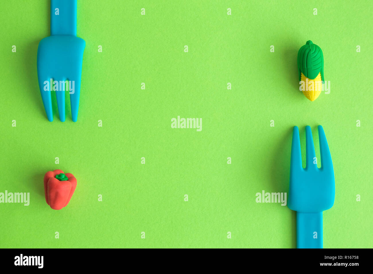 Flat lay of plastic forks with small rubber corn and pepper toys ...