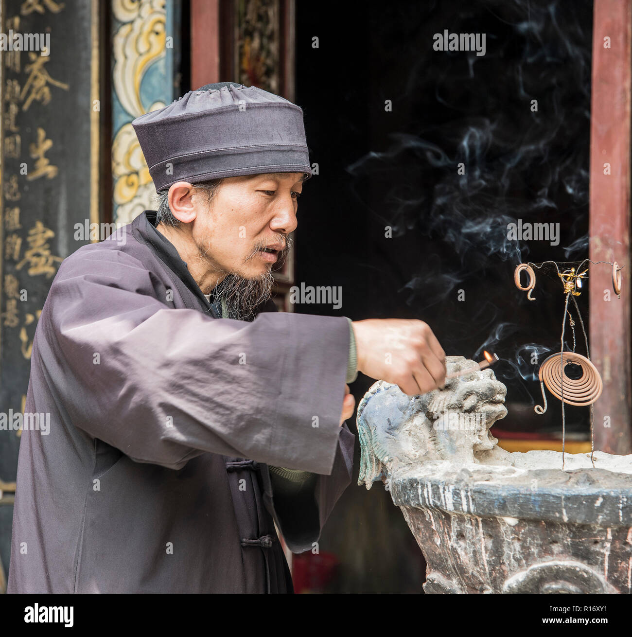 Chinese monk lighting incense stick going about his daily routine ...