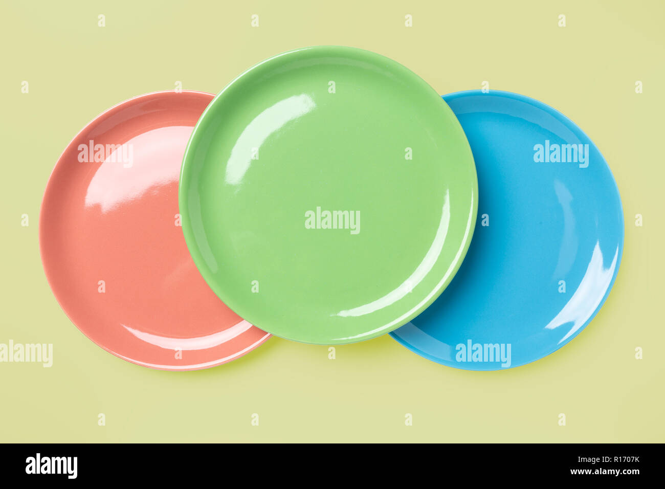 Blue, green and rose pastel colored plates on light yellow background ...