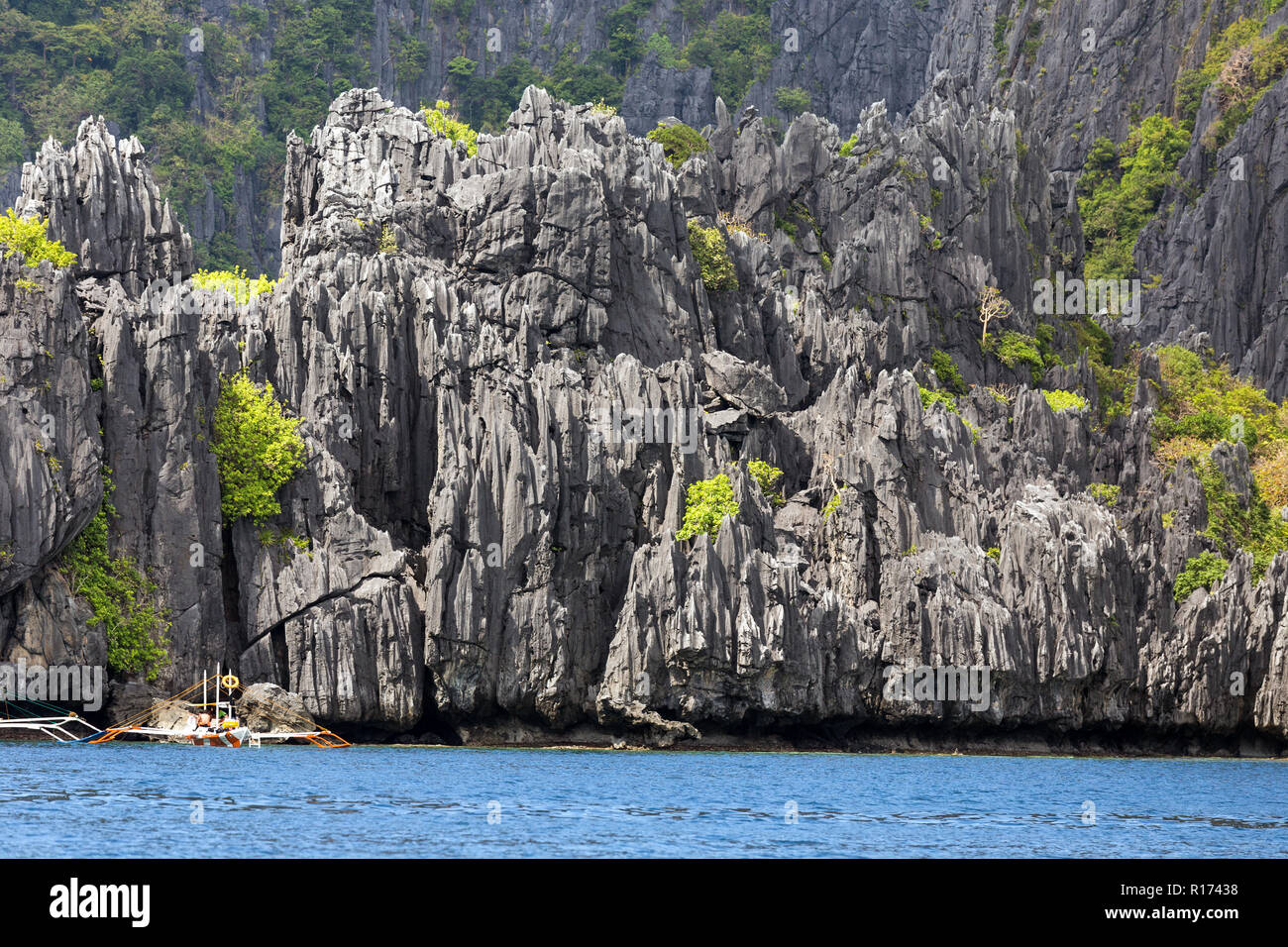 Huge limestone cliff coastline in Palawan with traditional Bangka boats ...