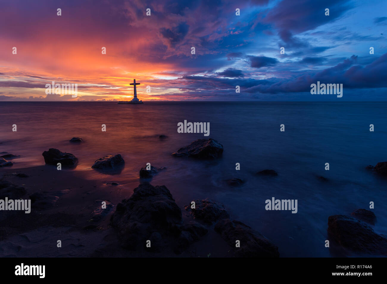 Catholic cross silhouette in a sunken cemetery at dusk, Camiguin island ...