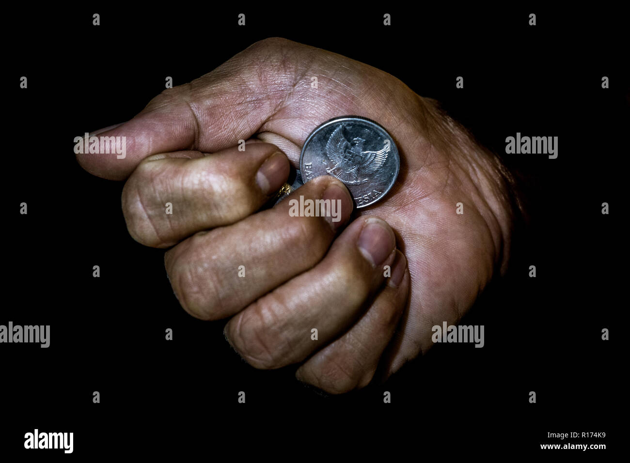 Indonesia rupiah coin in the hand of an asian person isolated. Concept ...
