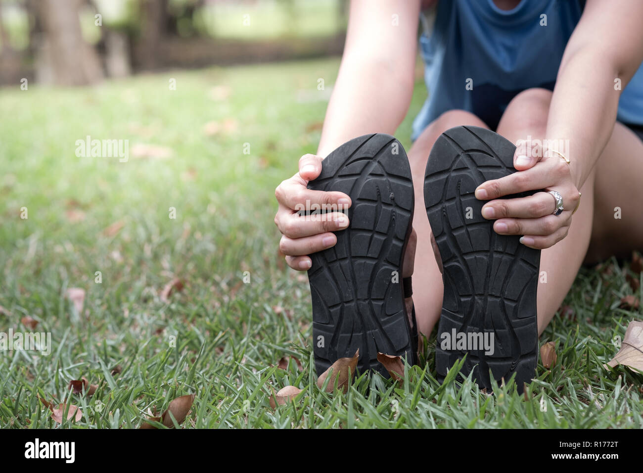 Hand of woman holding her feet and stretch the muscles in the park ...