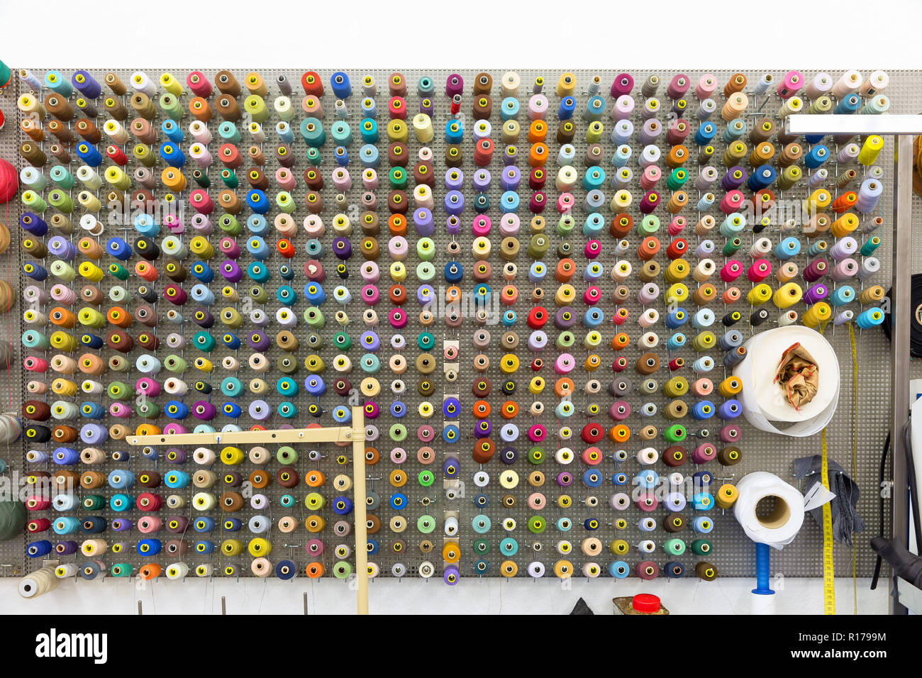 Workplace of a tailor with a wall full of spools of threads in many ...