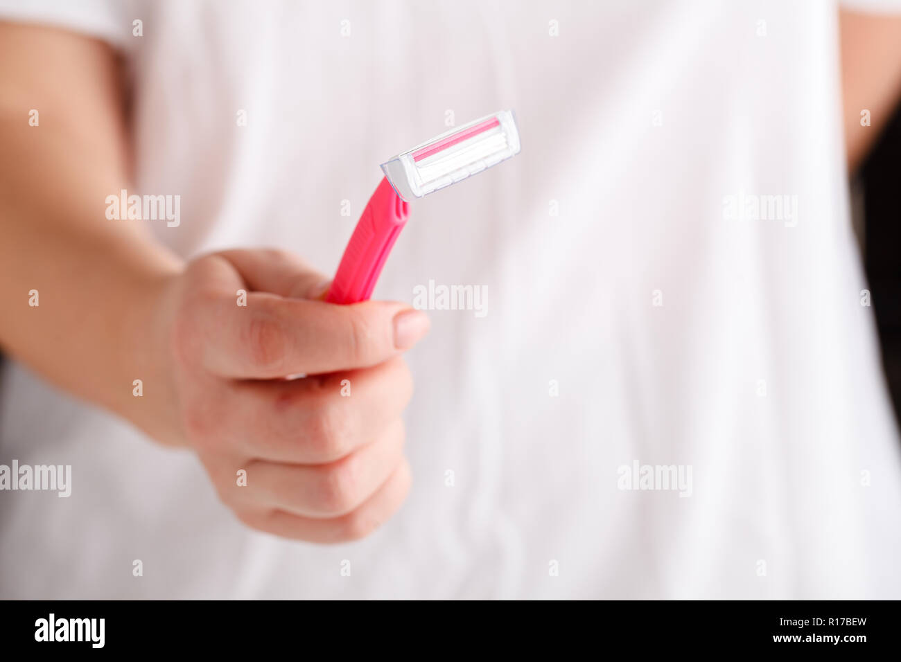 Disposable shaver in female hand on abstract blurred white background ...