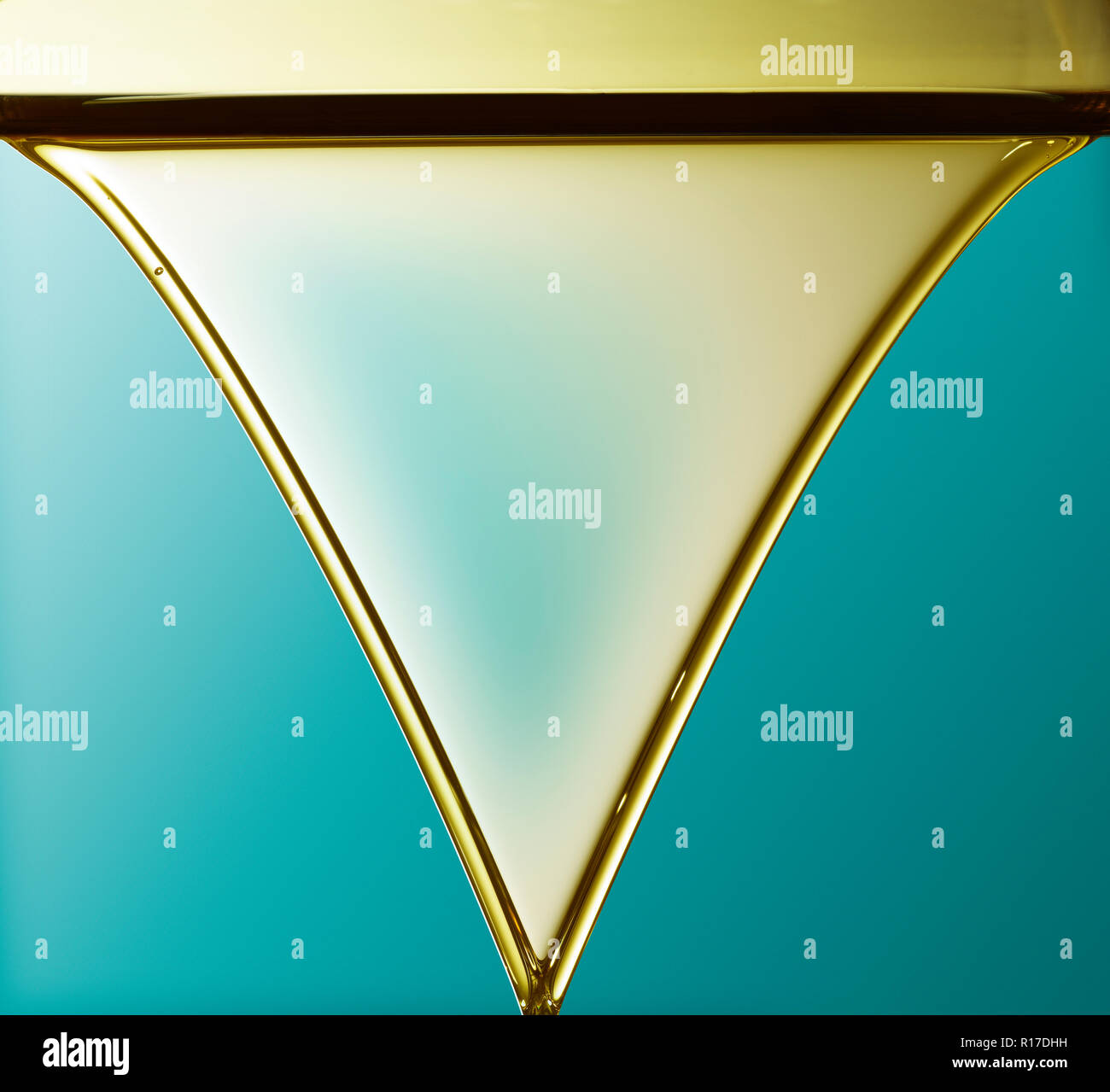 Golden coloured oil flowing into V shape against blue background Stock ...