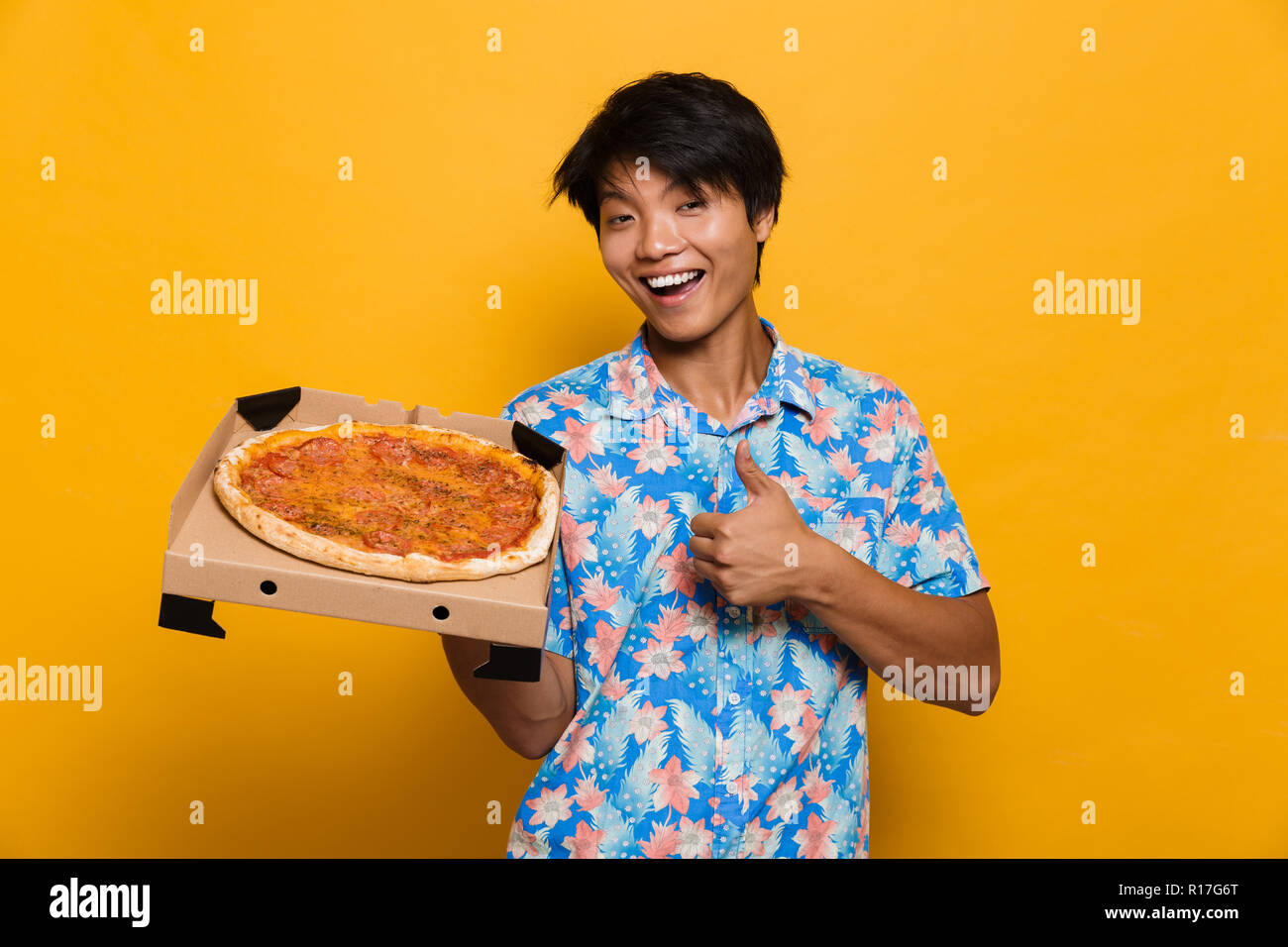 Image of excited happy young asian man standing isolated over yellow ...