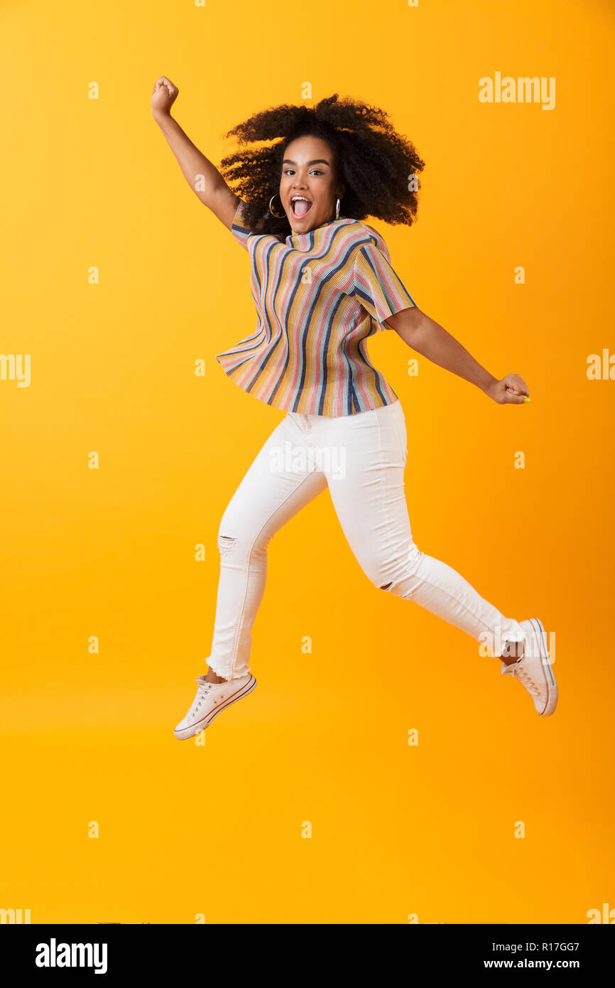 Image of emotional pretty african woman jumping isolated over yellow ...