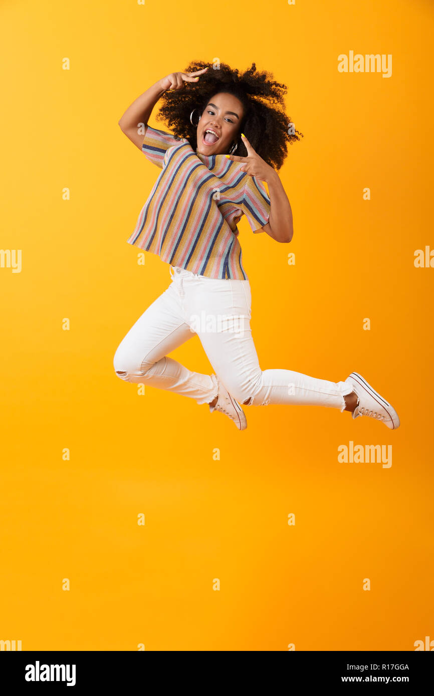 Image of emotional pretty african woman jumping isolated over yellow ...