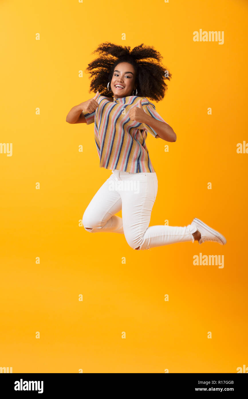 Image of emotional pretty african woman jumping isolated over yellow ...