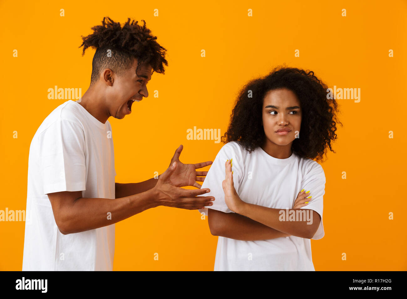 Portrait of an angry african couple standing isolated over yellow ...