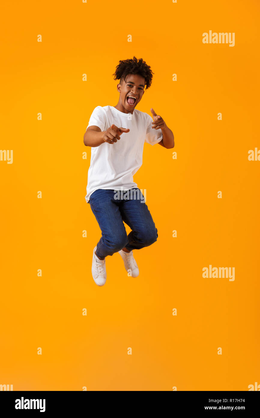 Image of happy young african man jumping isolated over yellow ...
