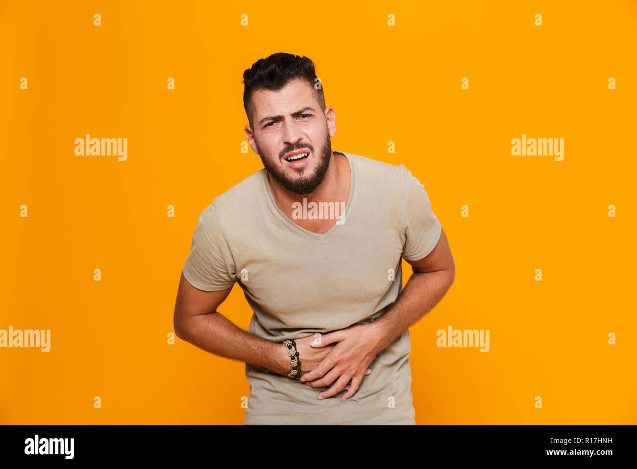 Portrait of a young casual man standing isolated over orange background ...