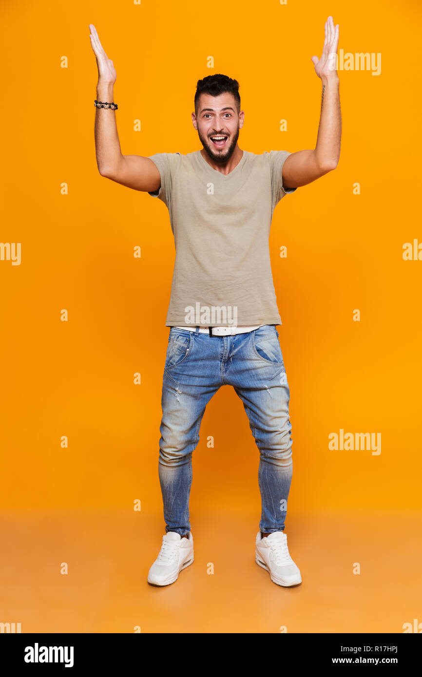 Full length portrait of a cheerful young casual man standing isolated ...