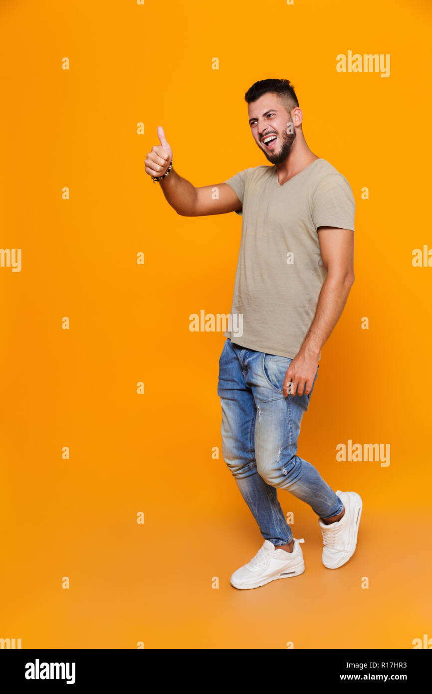 Full length portrait of a smiling young casual man standing isolated ...