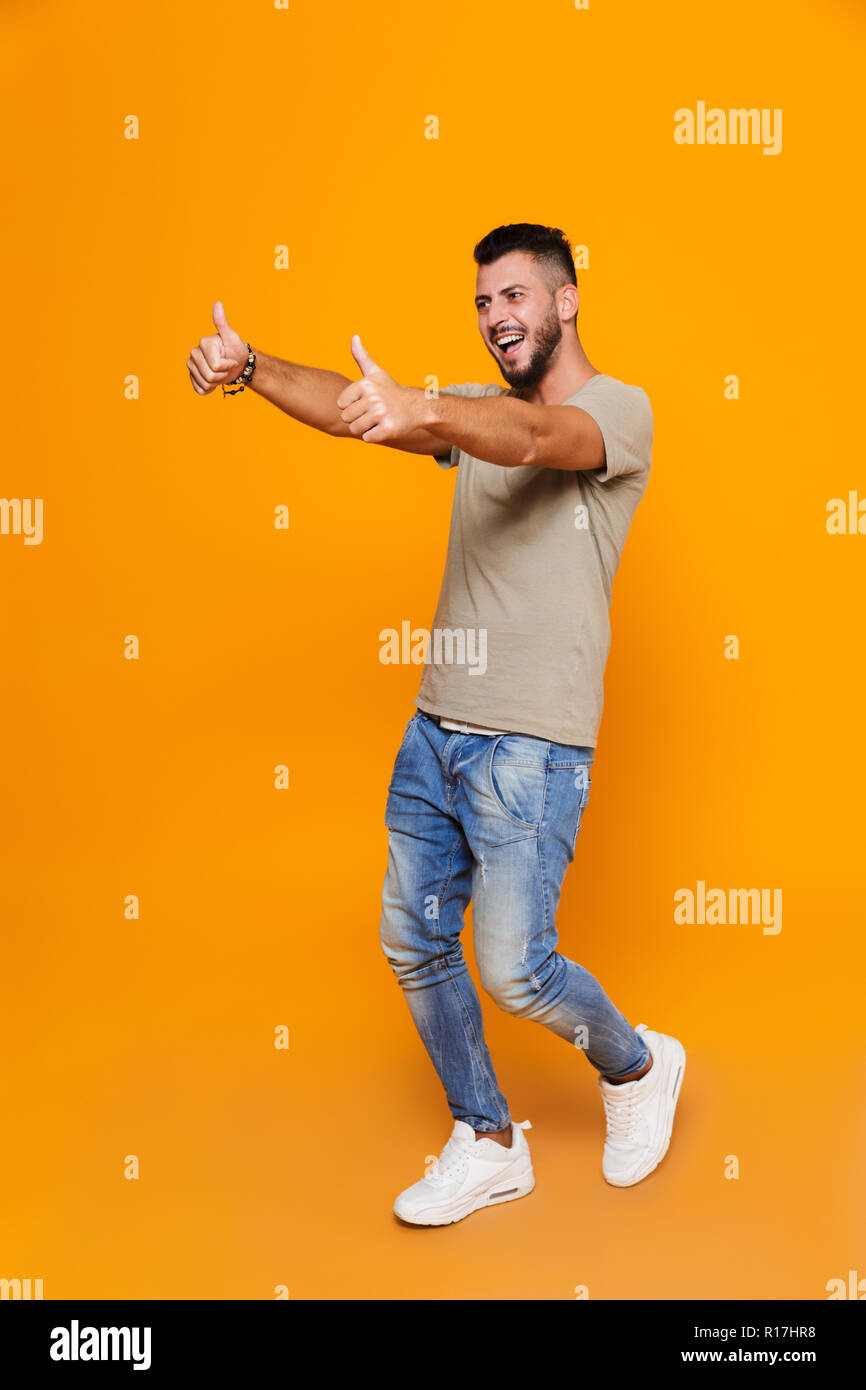 Full length portrait of a smiling young casual man standing isolated ...