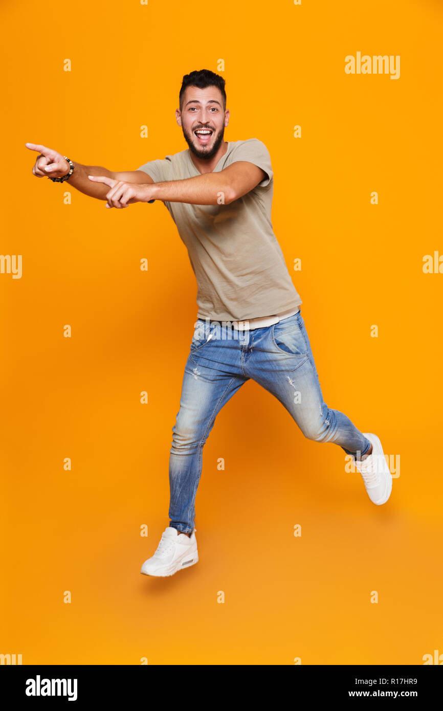 Full length portrait of a smiling young casual man jumping isolated ...