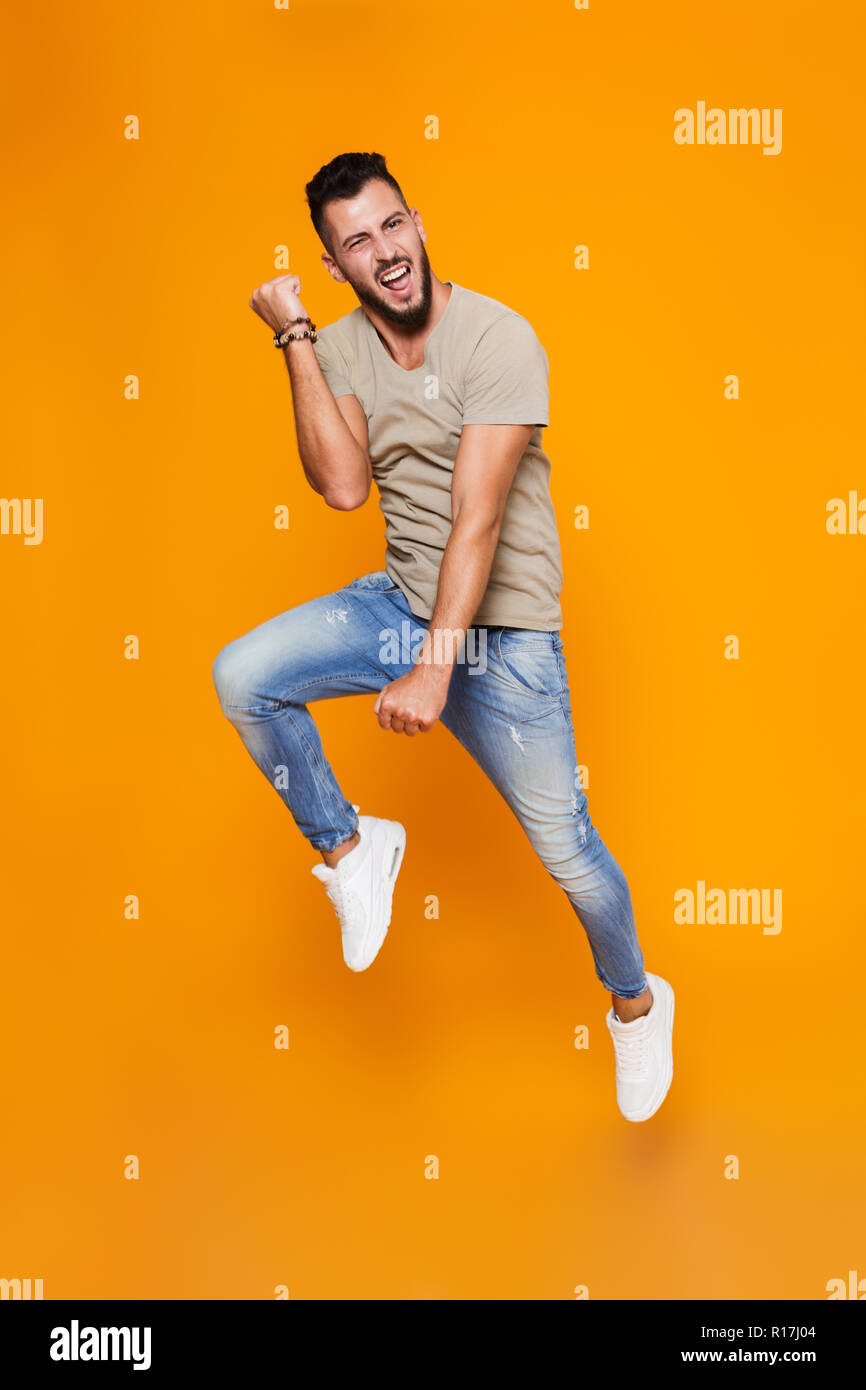 Full length portrait of an excited young casual man jumping isolated ...