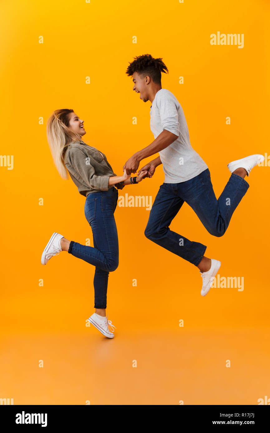Photo of happy young loving couple jumping isolated over yellow ...