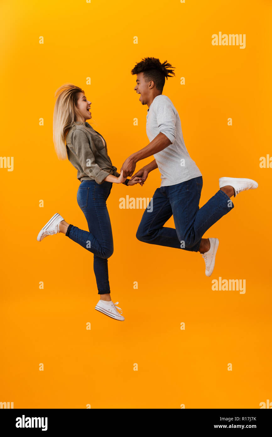 Photo of happy young loving couple jumping isolated over yellow ...