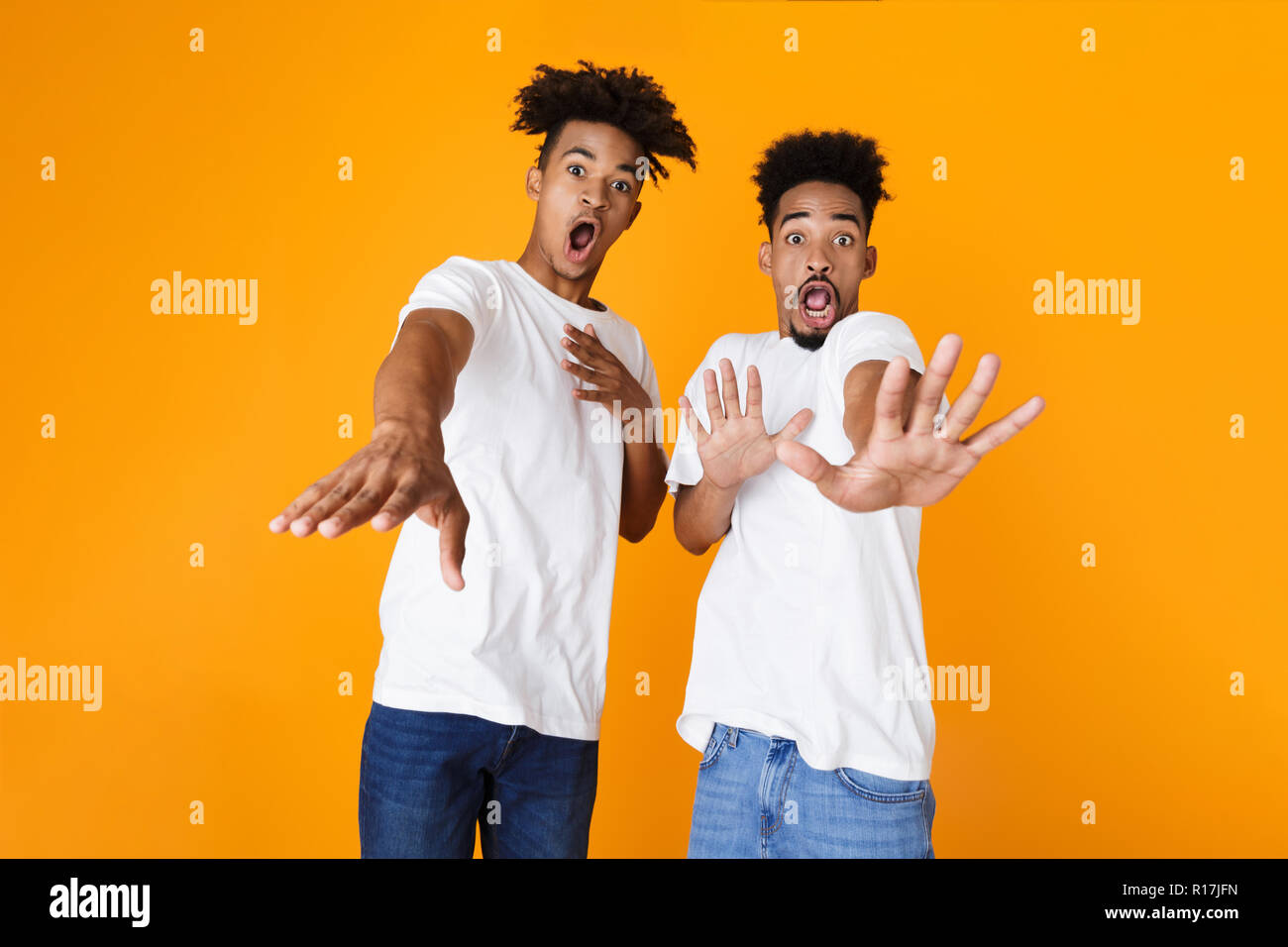 Two scared male african friends in t-shirts standing isolated over ...