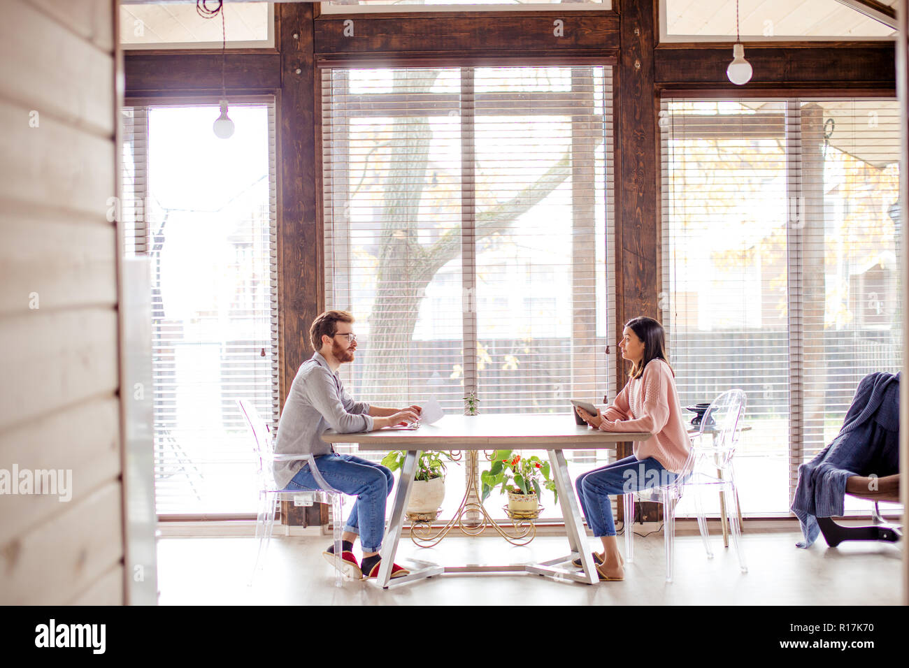A Man And A Woman Are Sitting At A Table Opposite Each Other Stock