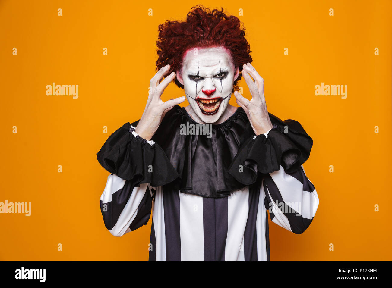 Scary angry man clown with red hair scream and looking to camera ...