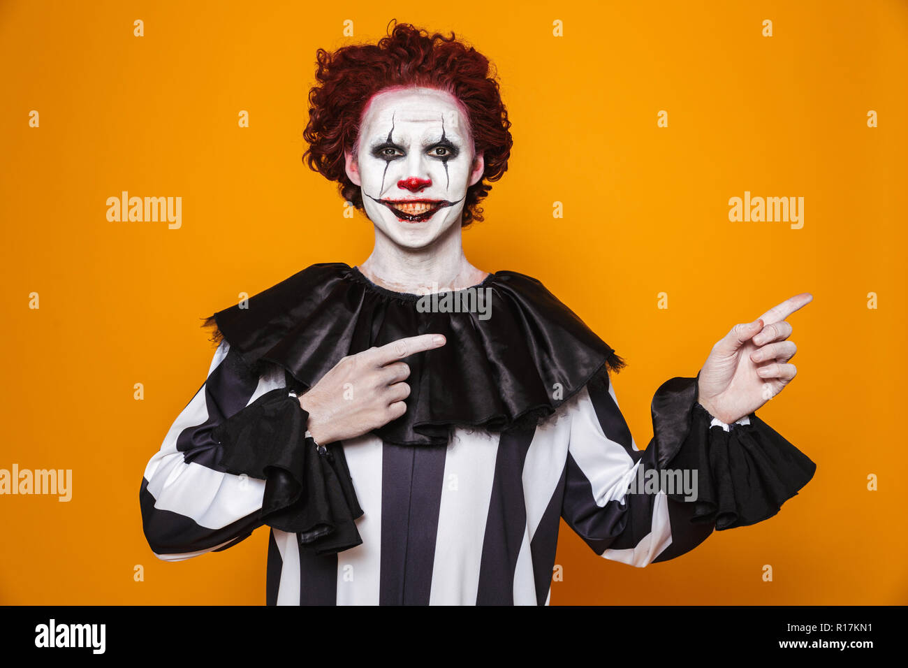 Smiling man clown in black and white costume looking camera and ...
