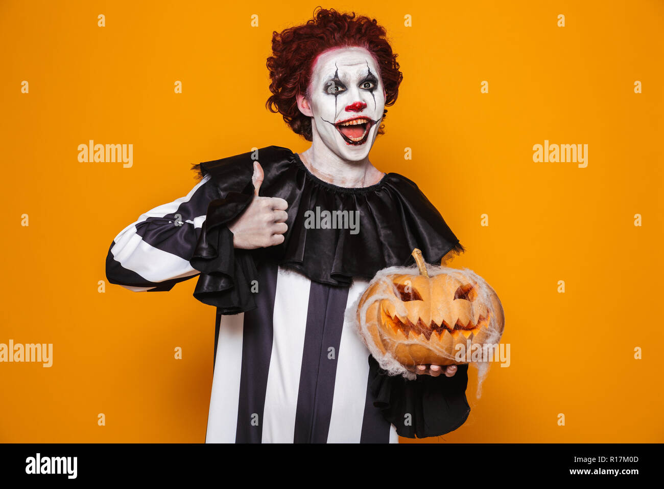 Angry man dressed in scary clown Halloween costume holding curved ...