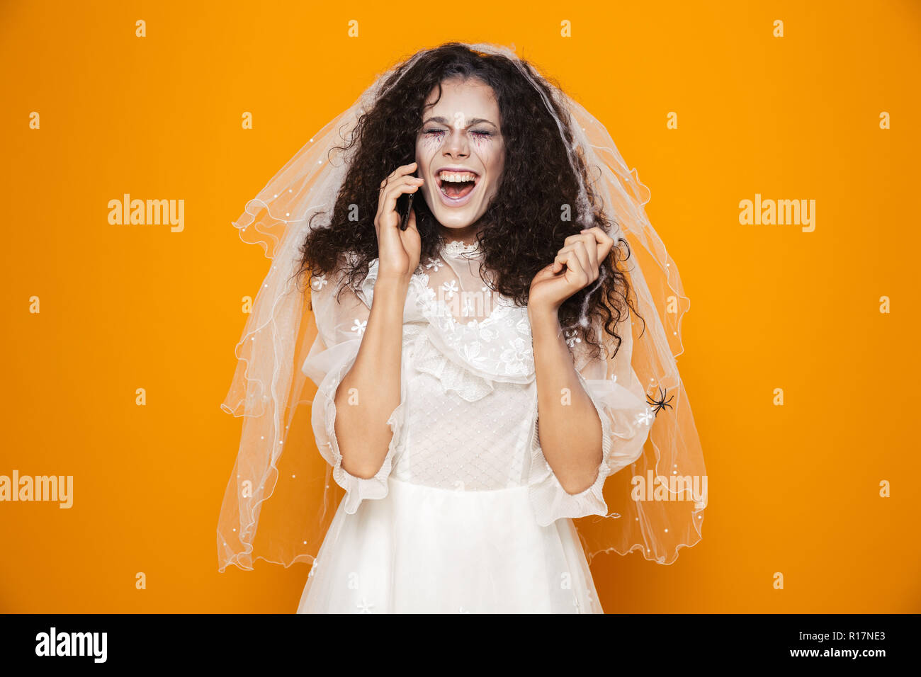 Happy brunette woman zombie in wedding dress and veil talking on ...