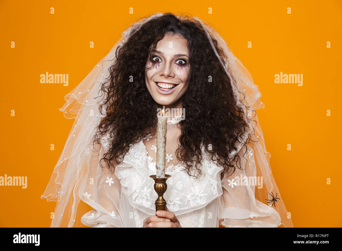 Cheerul beautiful dead bride in wedding dress holding candle and ...
