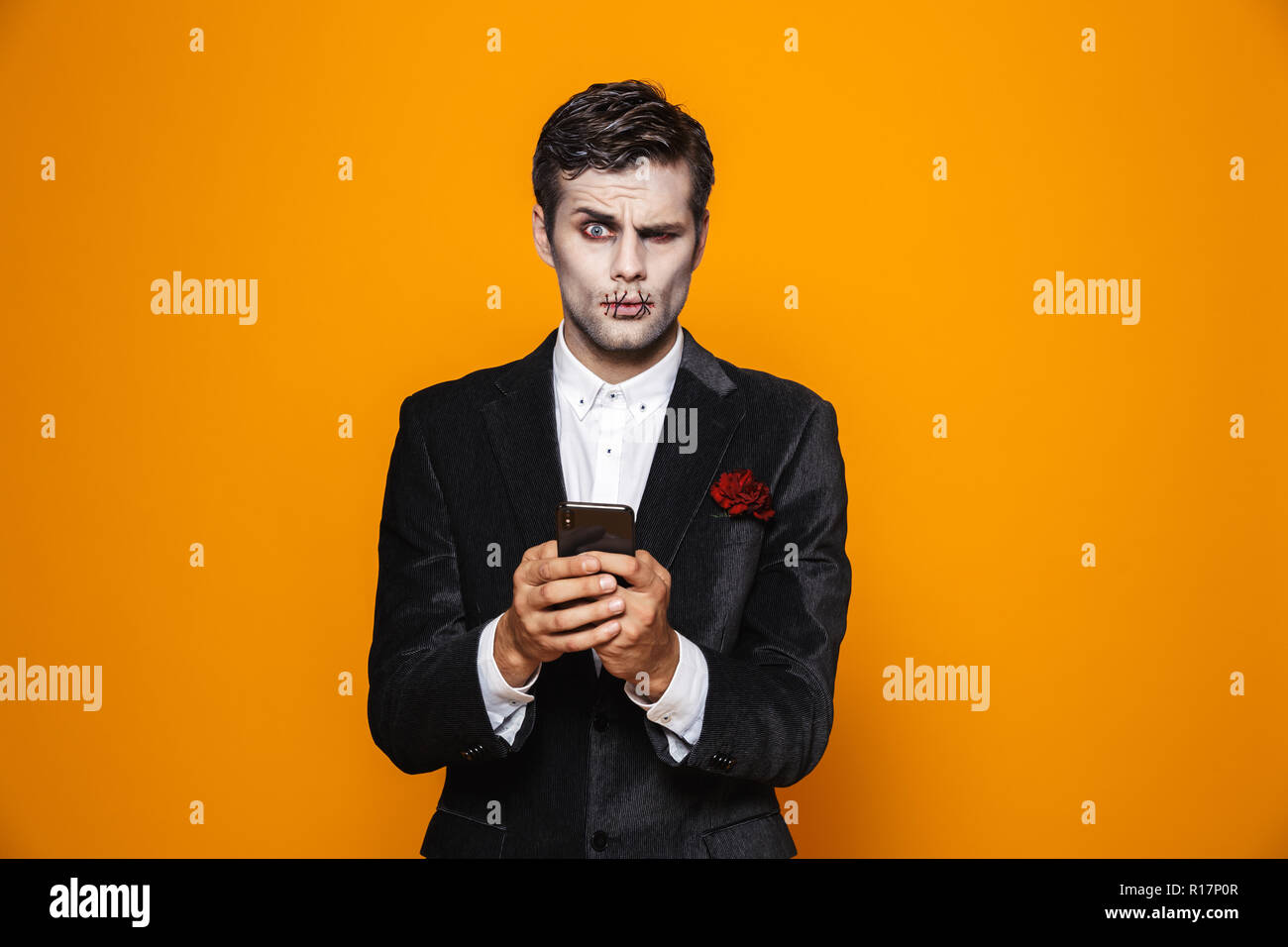 Shocked man zombie 20s in official suit looking camera and holding ...