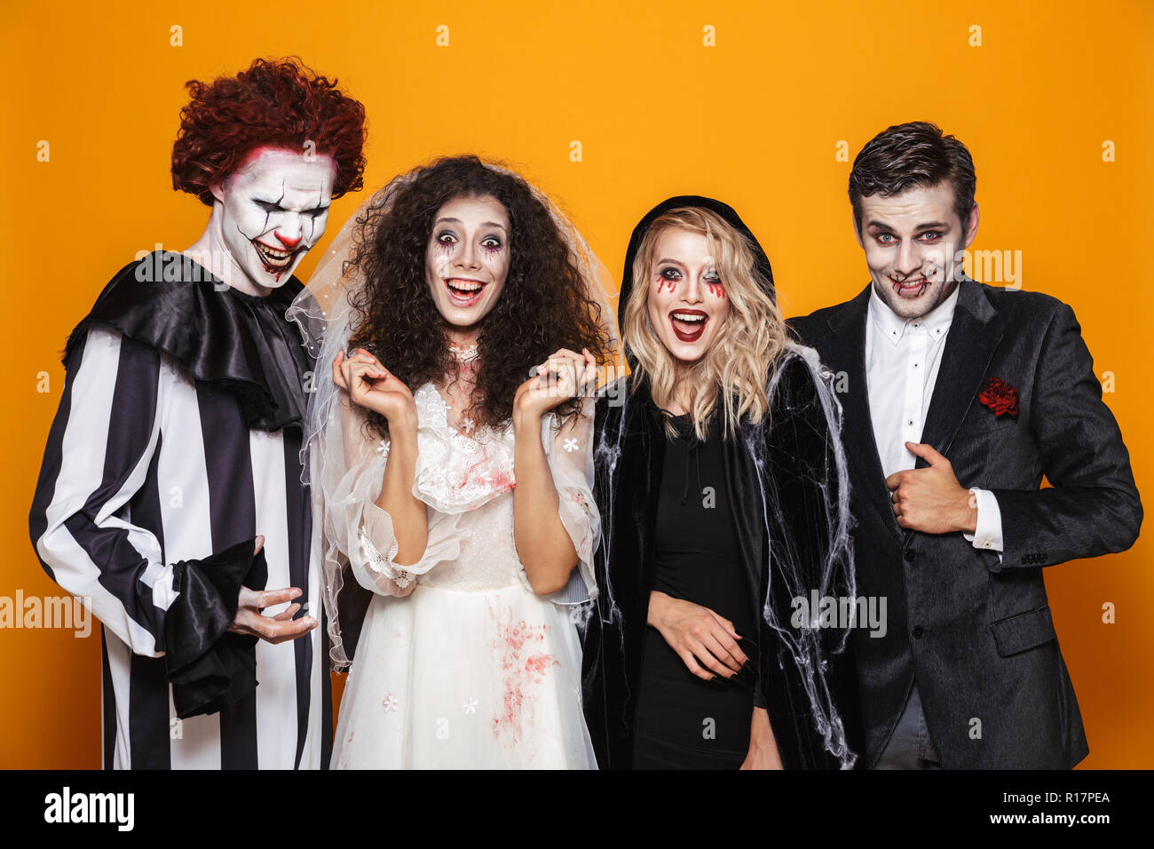 Group of cheerful friends dressed in scary costumes celebrating ...