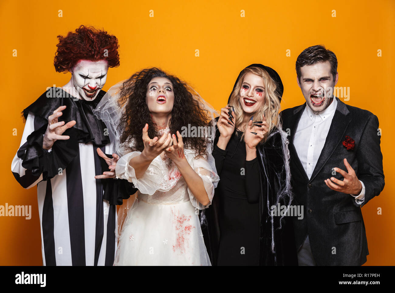 Group of smiling friends dressed in scary costumes celebrating ...