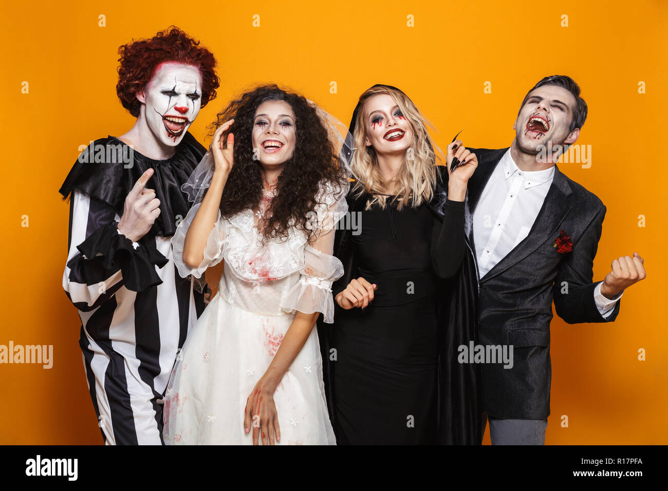 Group of laughing friends dressed in scary costumes celebrating ...