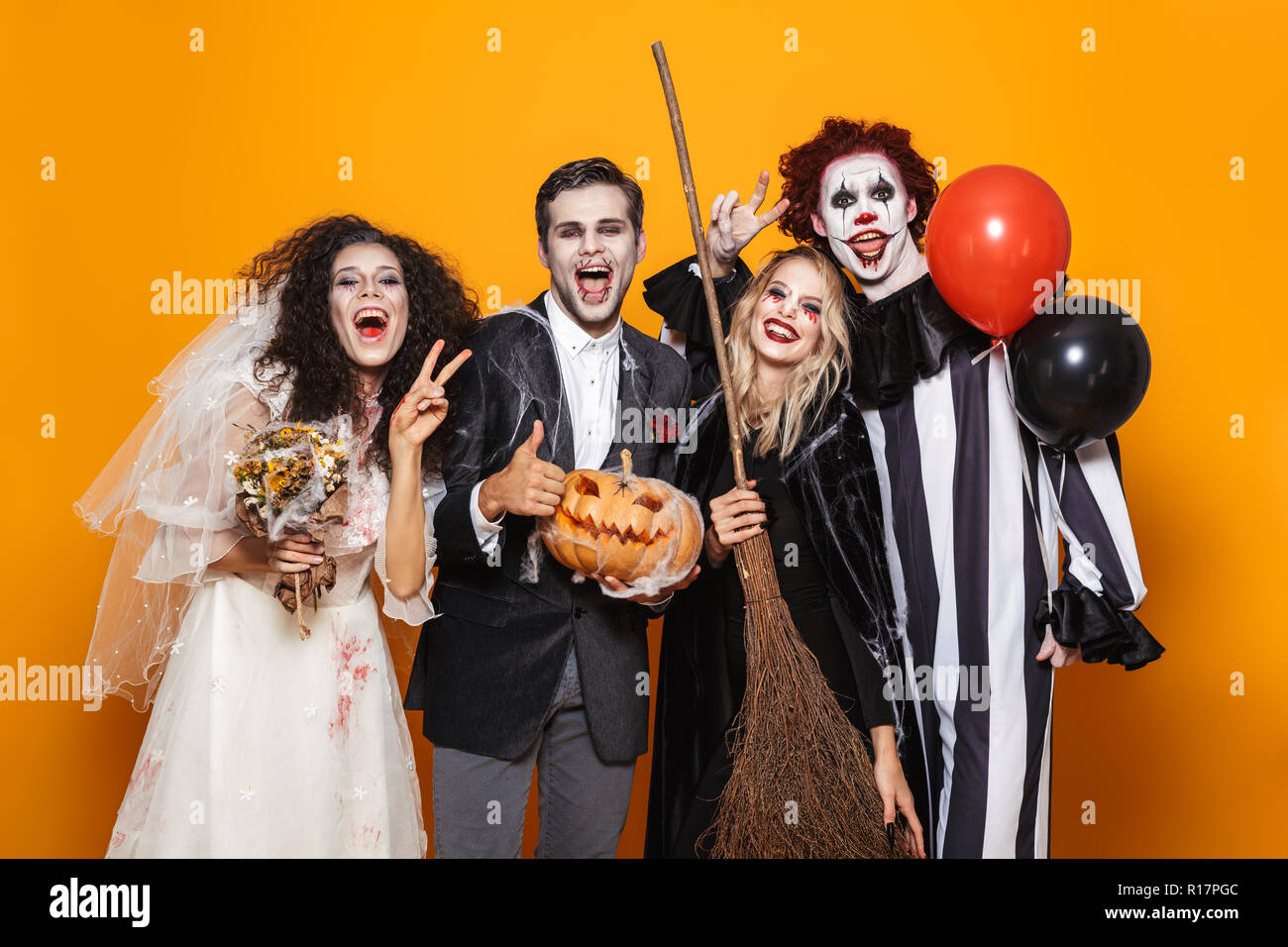 Group of cheerful friends dressed in scary costumes celebrating ...