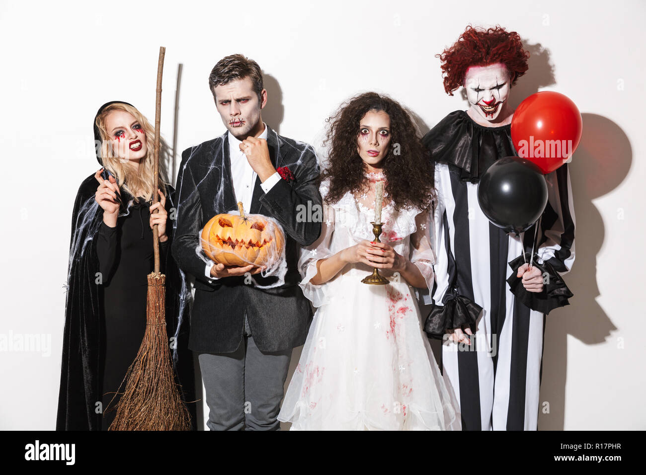 Group of cheerful friends dressed in scary costumes celebrating ...