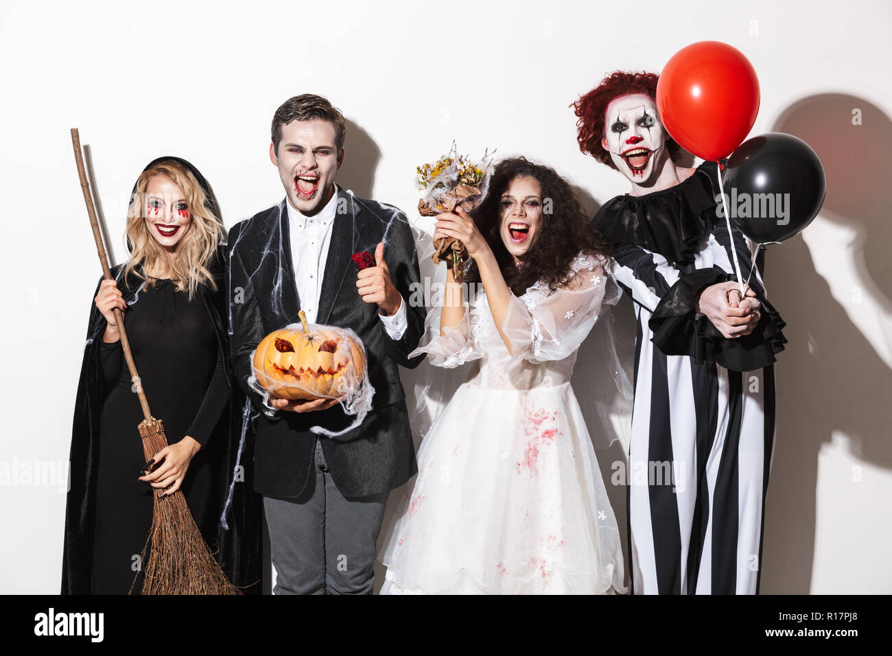 Group of joyful friends dressed in scary costumes celebrating Halloween ...