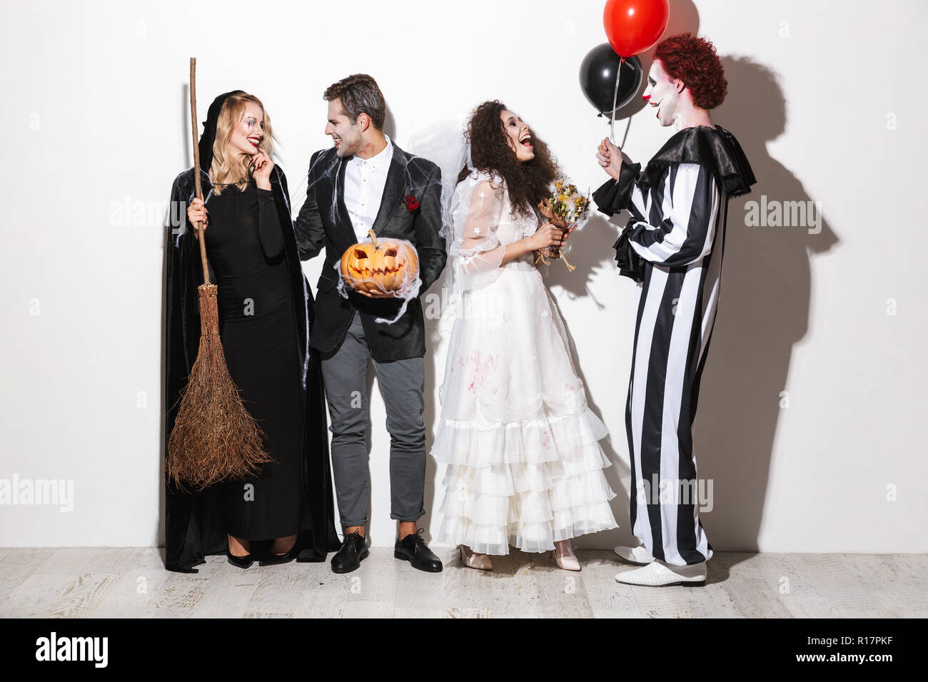 Group of smiling friends dressed in scary costumes celebrating ...