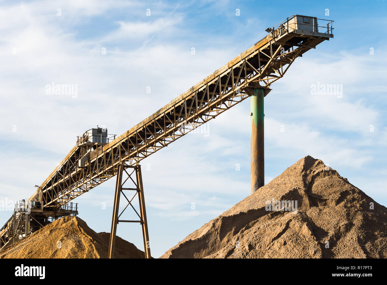 A conveyor system and mounds of sand at an industrial plant Stock Photo ...
