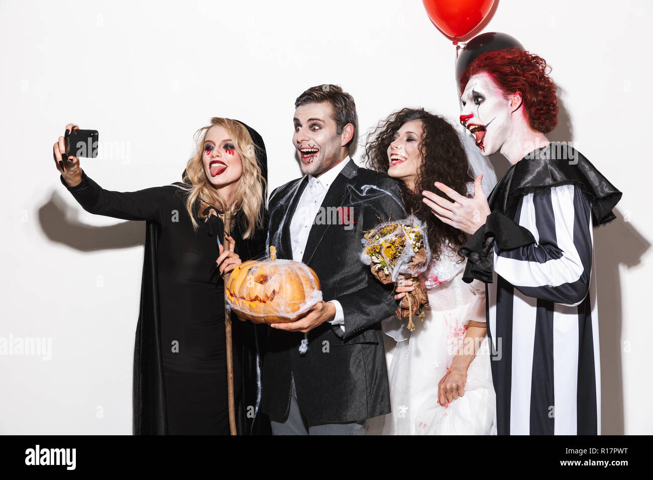 Group of joyful friends dressed in scary costumes celebrating Halloween ...