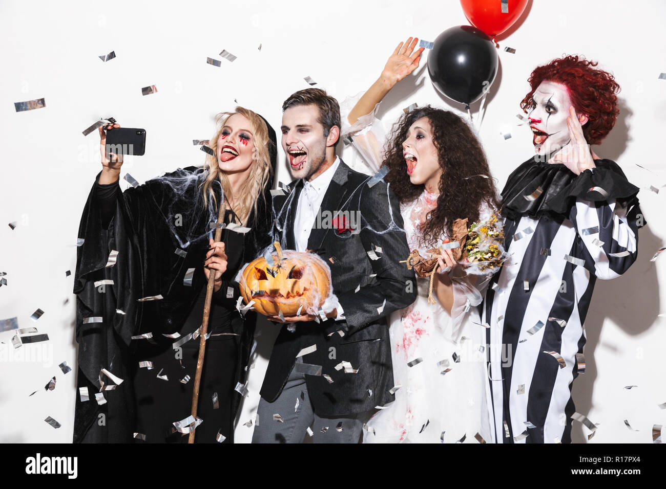 Group of friends dressed in scary costumes celebrating Halloween under ...