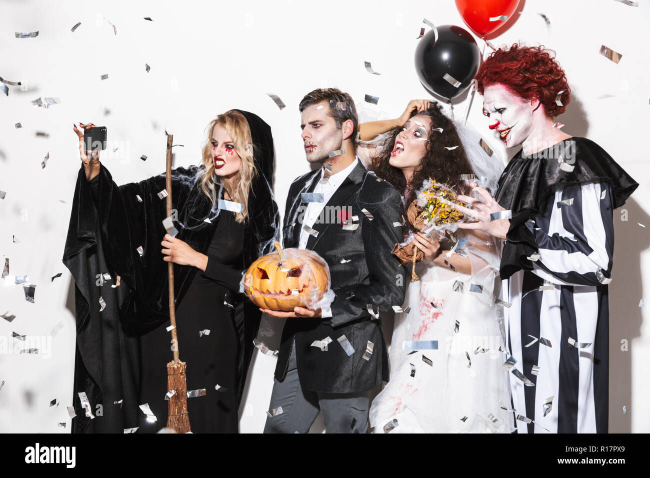 Group of excited friends dressed in scary costumes celebrating ...