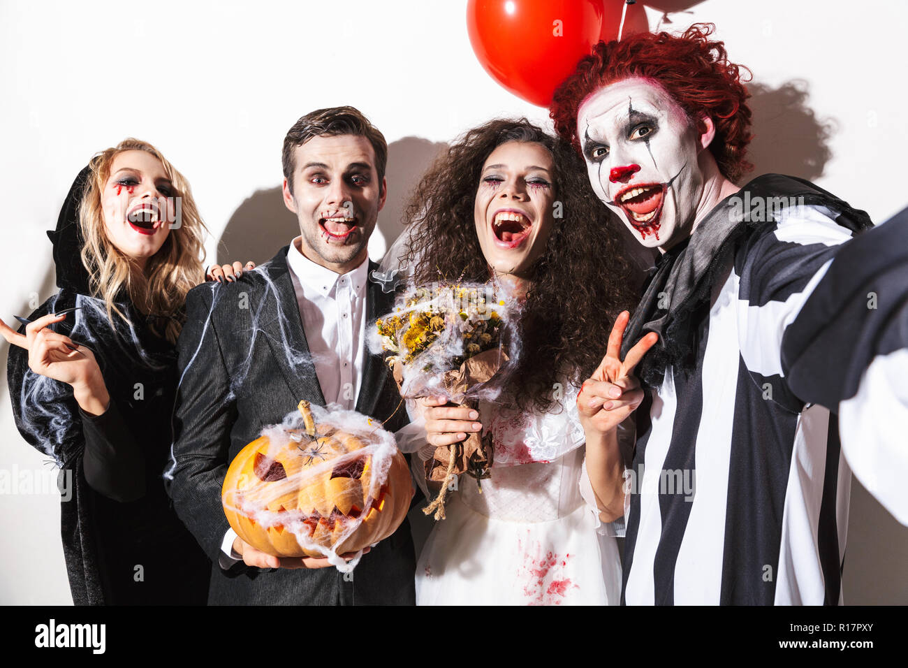 Group of excited friends dressed in scary costumes celebrating ...
