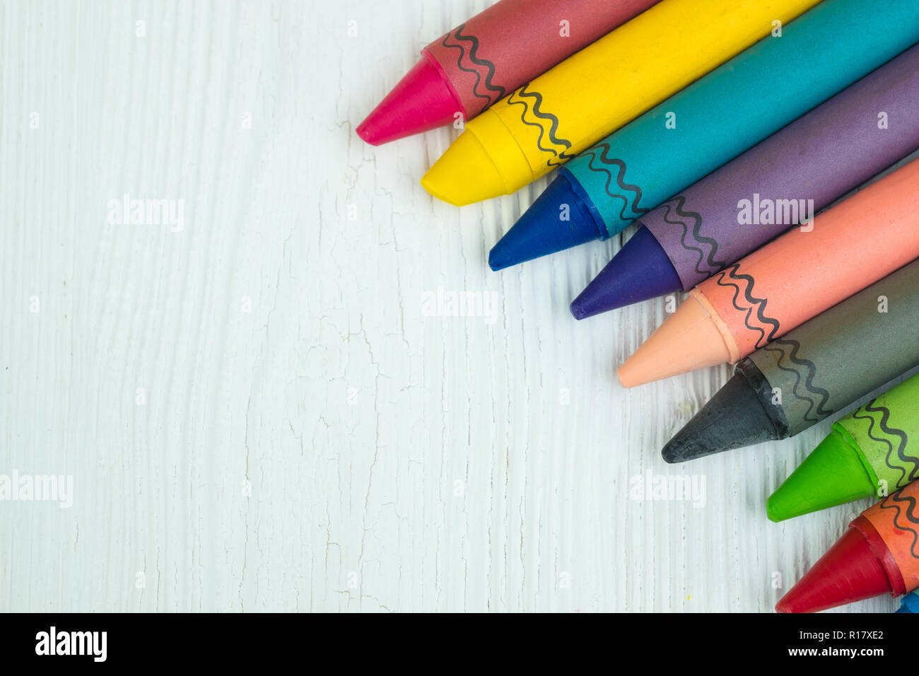 Colourful wax crayons pencils on white wood table with copy space for ...