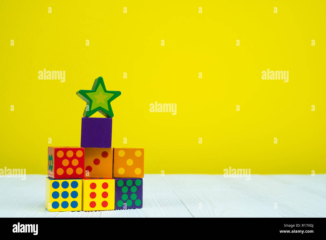 Square block puzzle toy on table with yellow wall background Stock Photo - Alamy