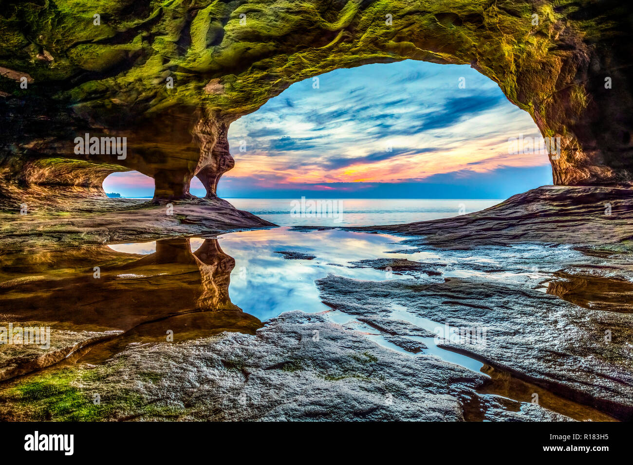 The sun sets on Lake Superior as photographed from a sea cave on a ...